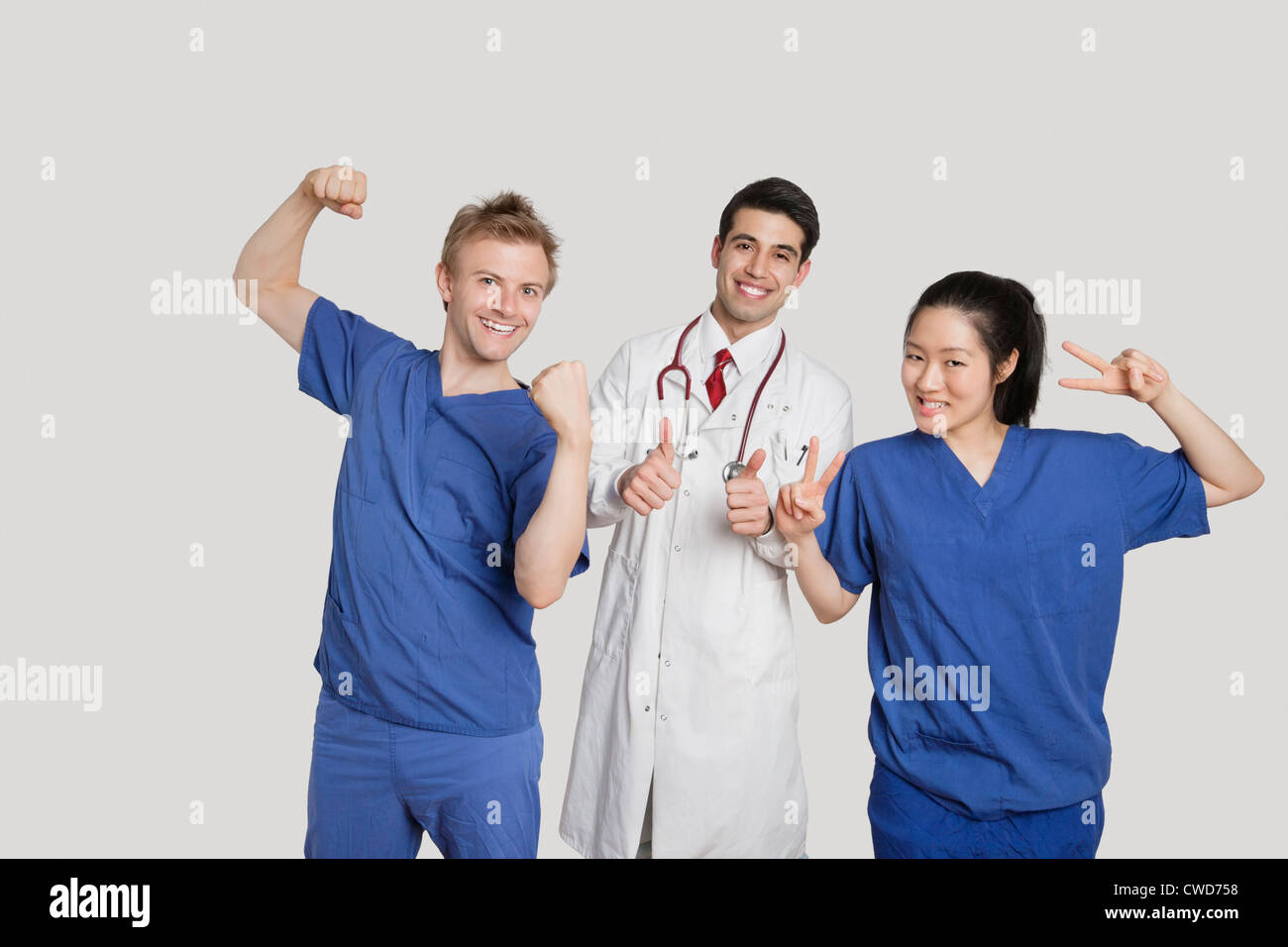 Portrait of a cheerful medical team gesturing over gray background ...