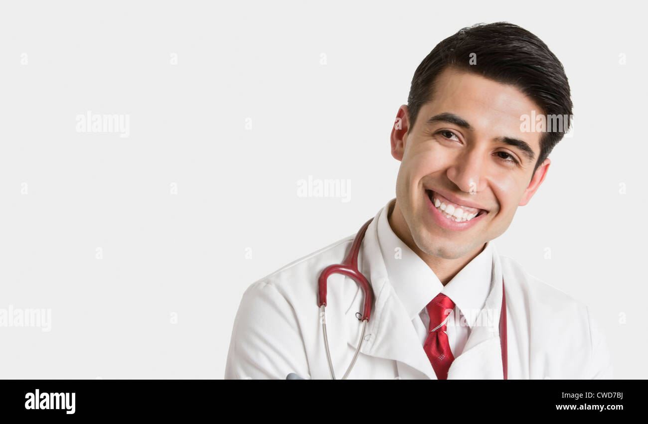 Cheerful Indian male doctor looking sideways over light gray background ...