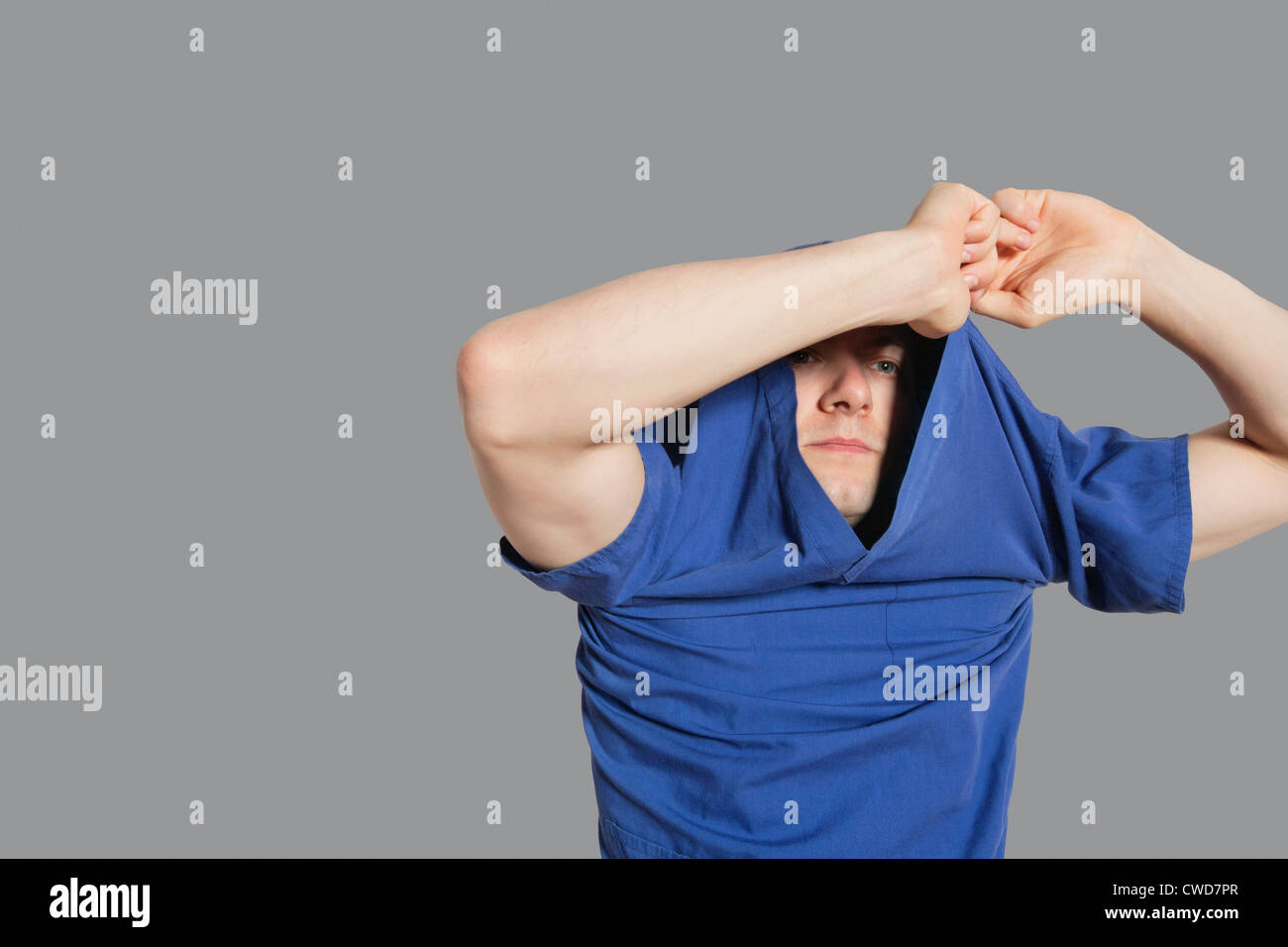 Young man removing t-shirt over colored background Stock Photo - Alamy