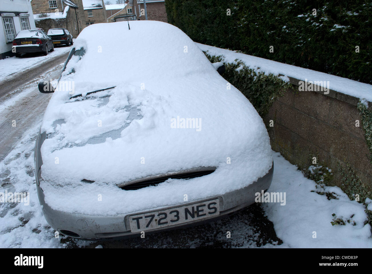 Snow covered car next to wall Stock Photo - Alamy
