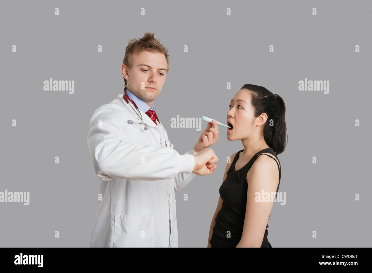 Doctor checking temperature of female patient Stock Photo - Alamy