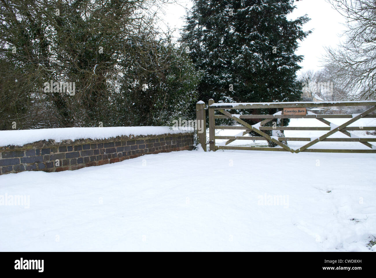 Snow covered entrance to garden with wide wooden gate and low brick ...