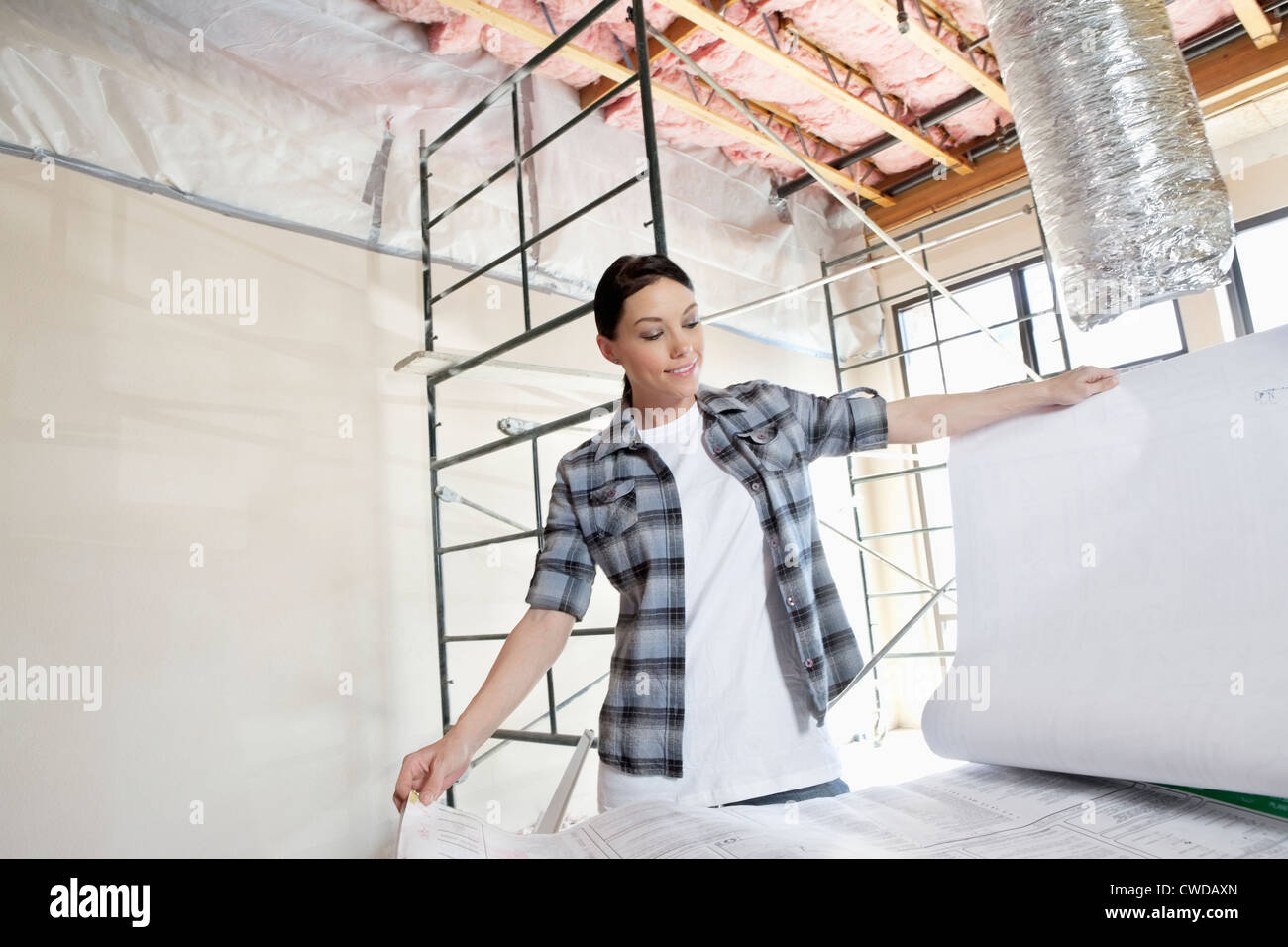 Beautiful mid adult contractor looking at building plans at ...