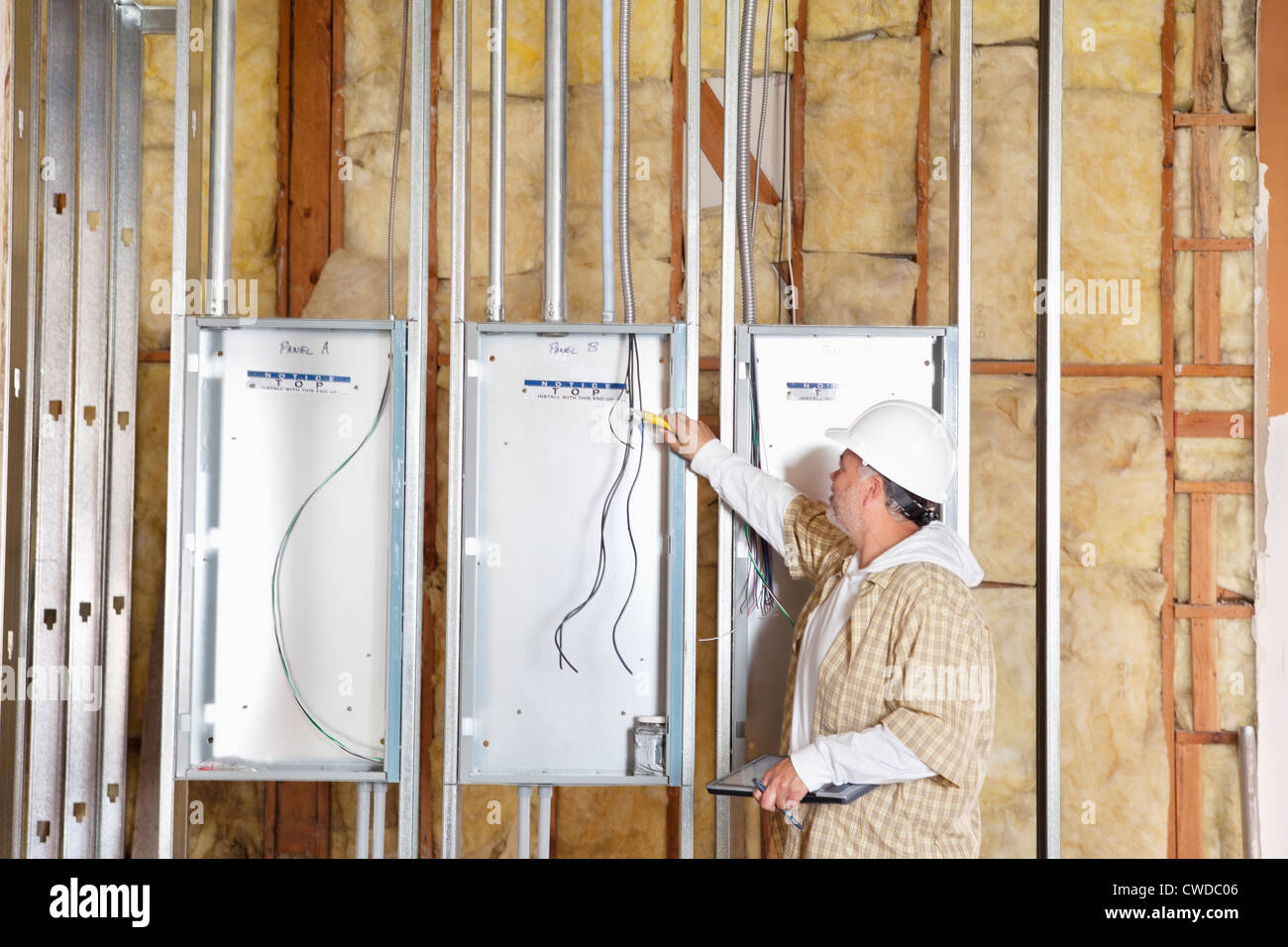 Male construction worker checking electric meters at construction site ...