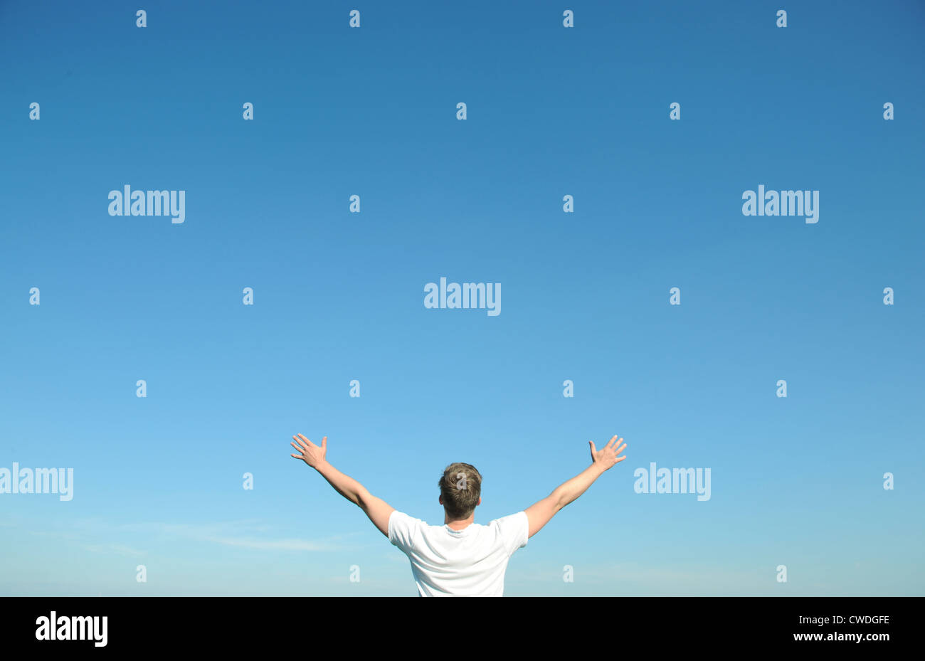 Young man in white t-shirt, arms open and blue sky Stock Photo - Alamy