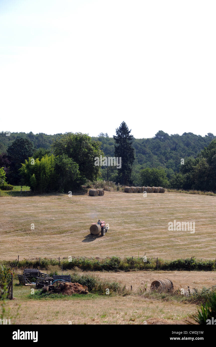 Tractor gathering hay bales on a farm in the Lot Region of South West ...