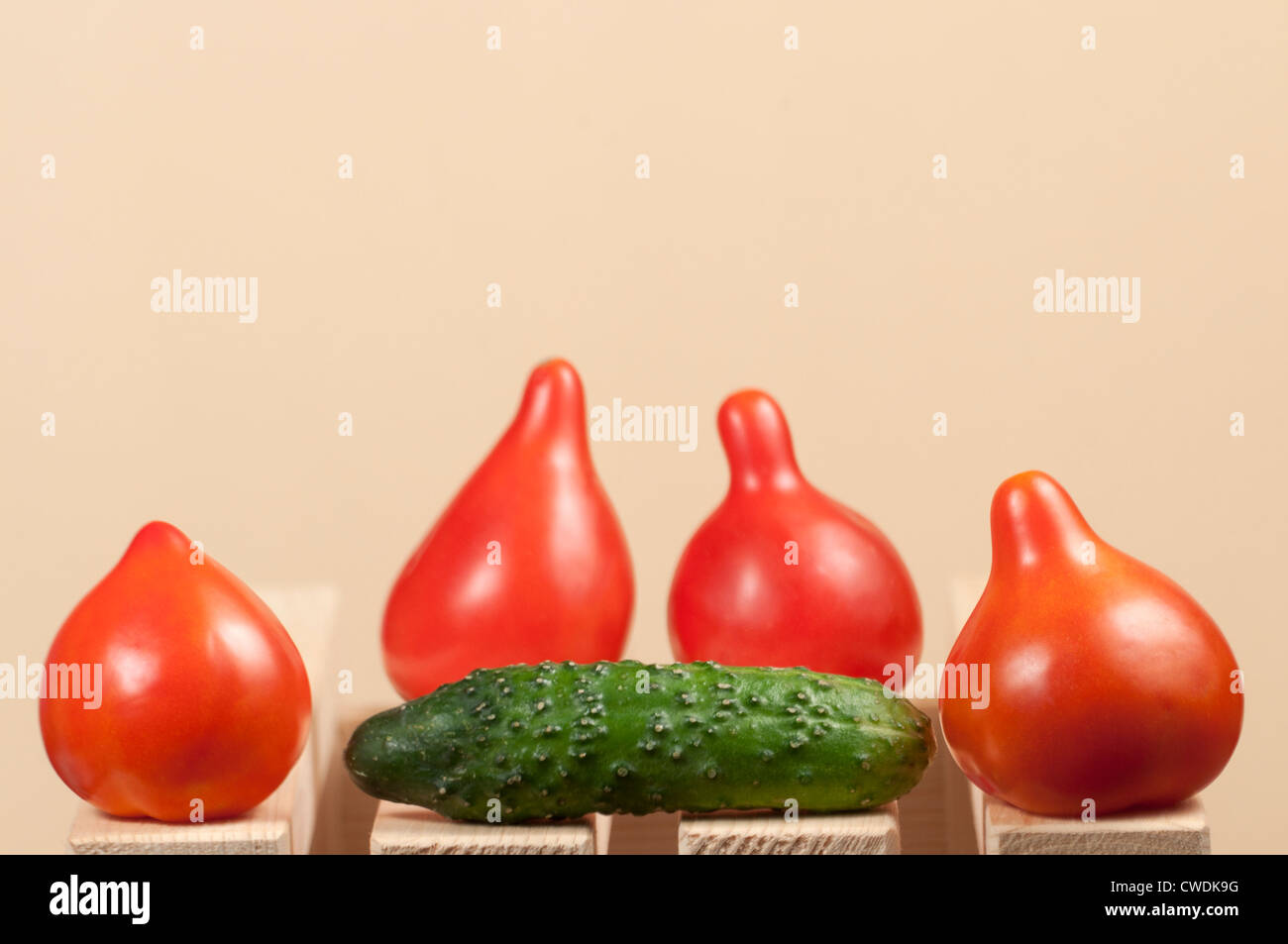 Four red tomatoes and cucumber on a wooden table Stock Photo - Alamy