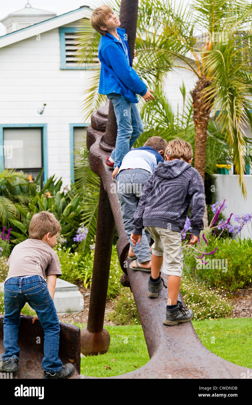 Boys playing on boat anchor Stock Photo - Alamy