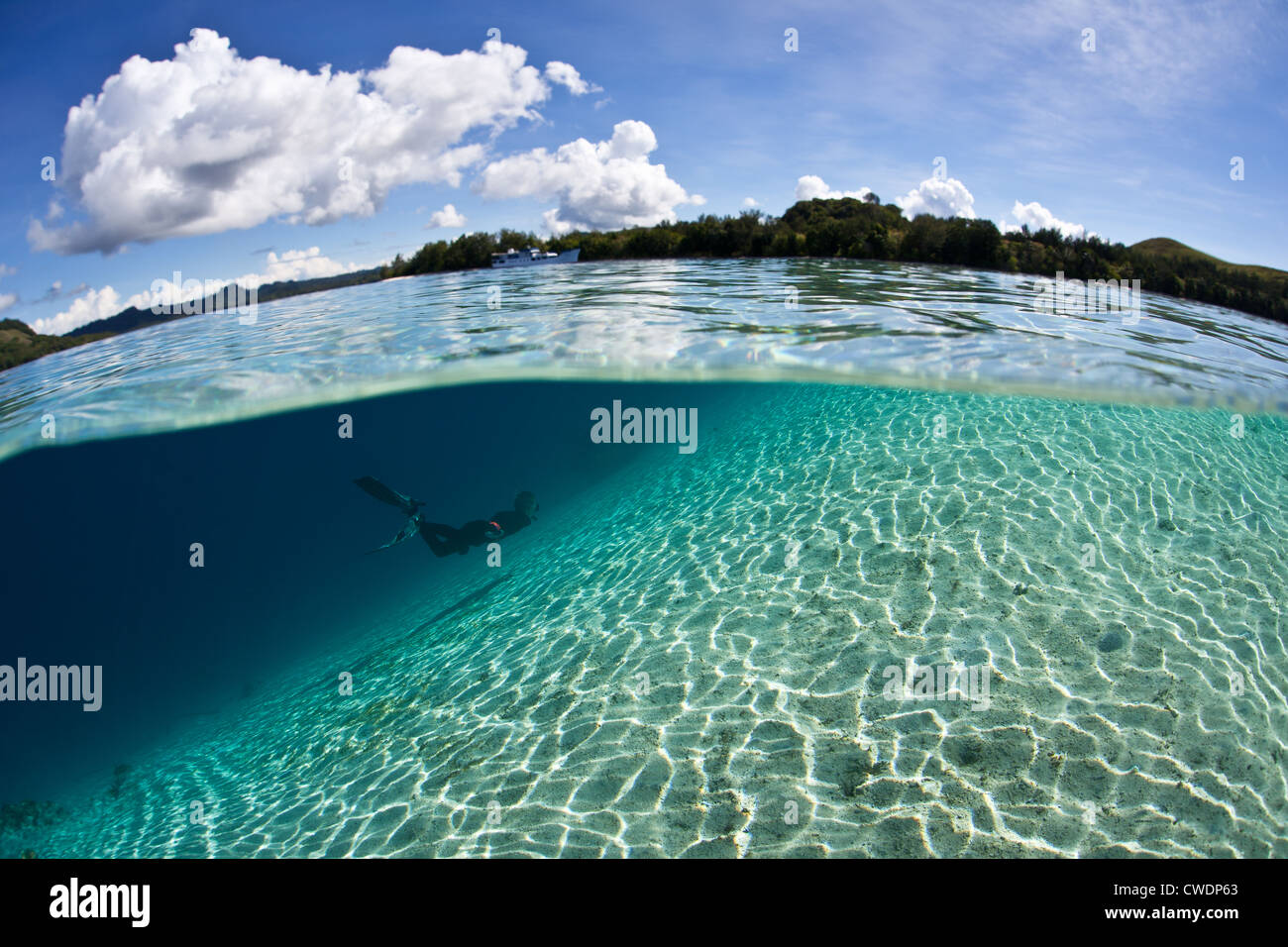 A freediver descends along the edge of a sandy slope. Florida Islands ...
