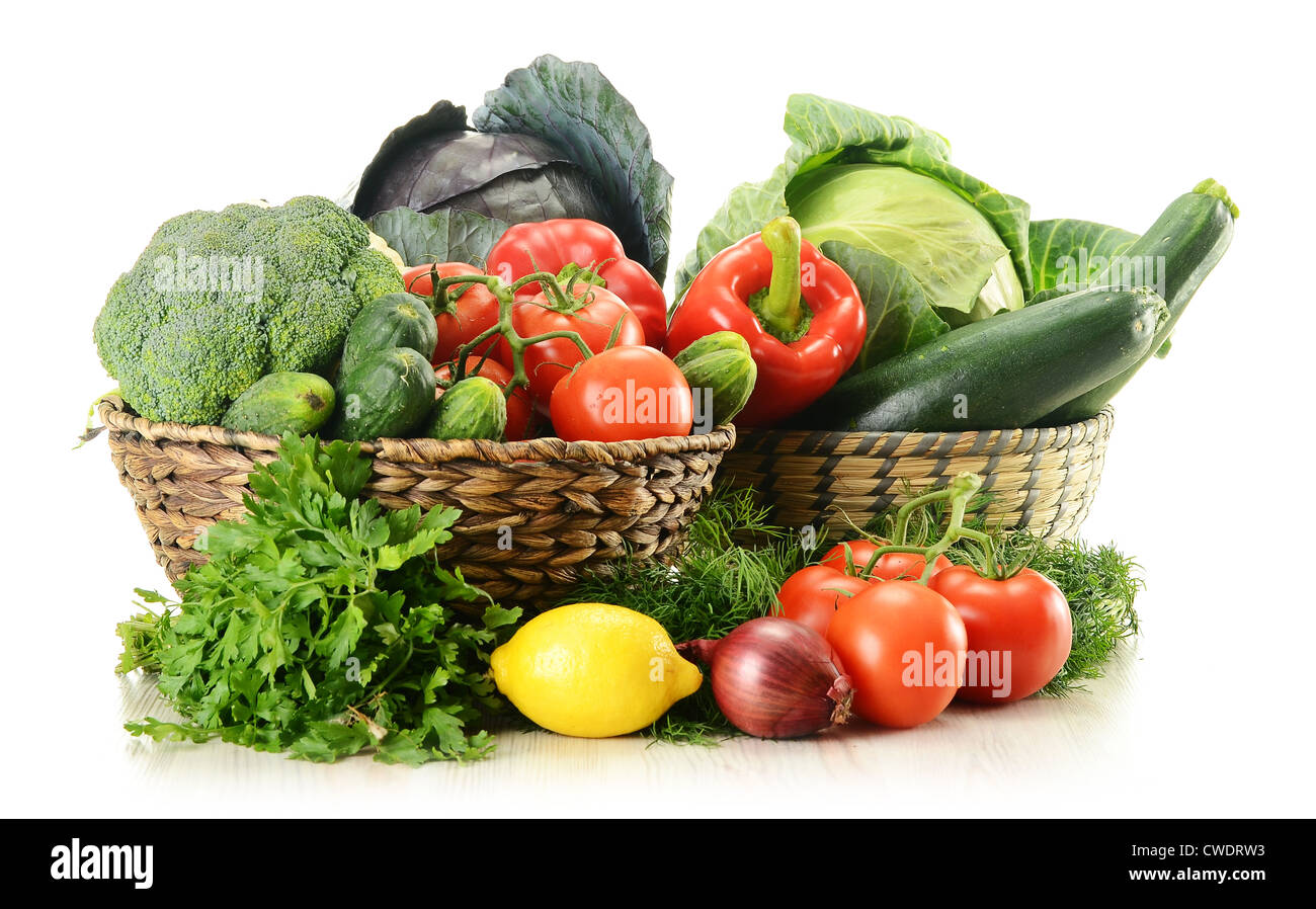 Composition with raw vegetables and wicker baskets isolated on white ...