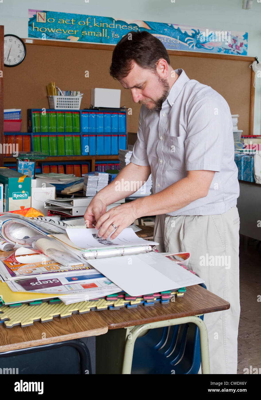 Young male Elementary school teacher organizes and reviews supplies and ...