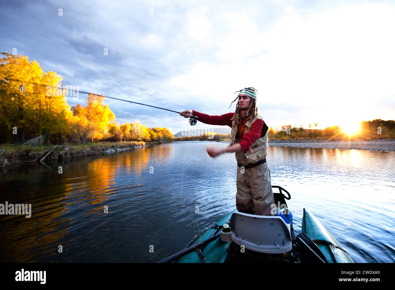 A fly fisher casting his line out of a boat while fly fishing ...