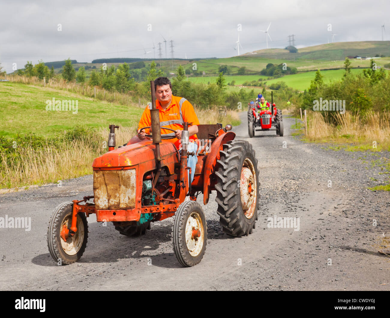 Enthusiast driving an orange vintage BMC Mini tractor during an ...