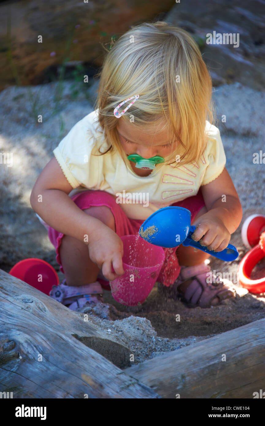 Child blond girl baby playing with sand in sandbox Stock Photo - Alamy