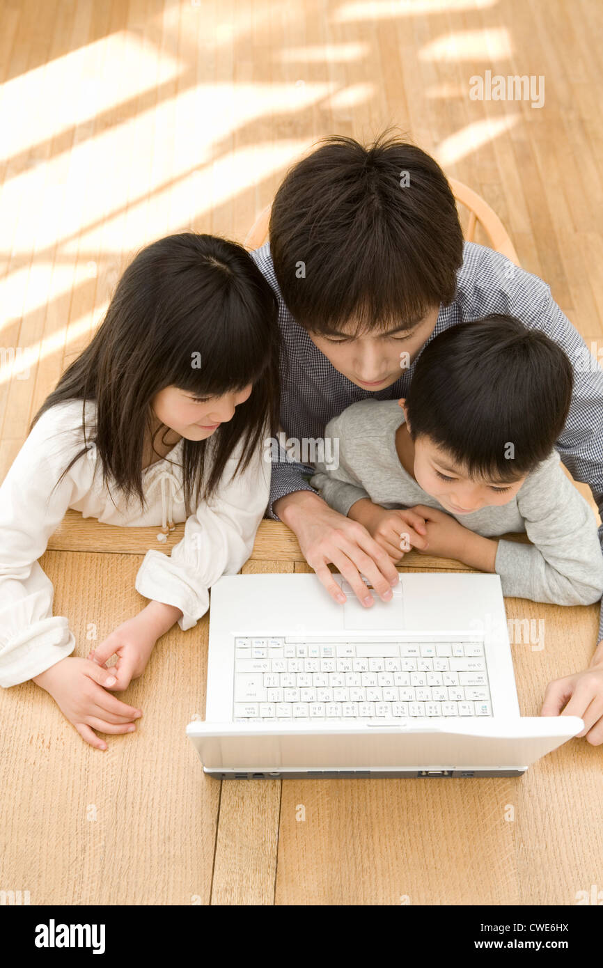 Father using laptop with two children Stock Photo - Alamy