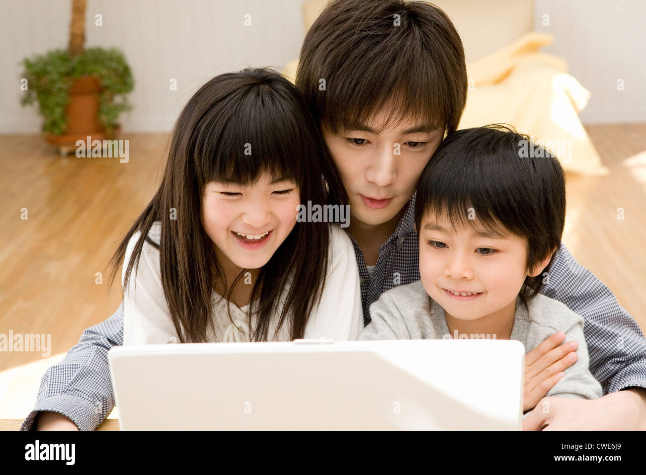 Father using laptop with two children Stock Photo - Alamy