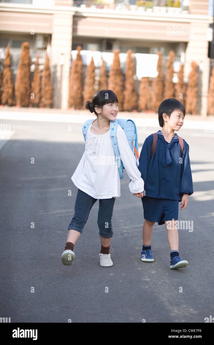 Two kids walking on road Stock Photo - Alamy
