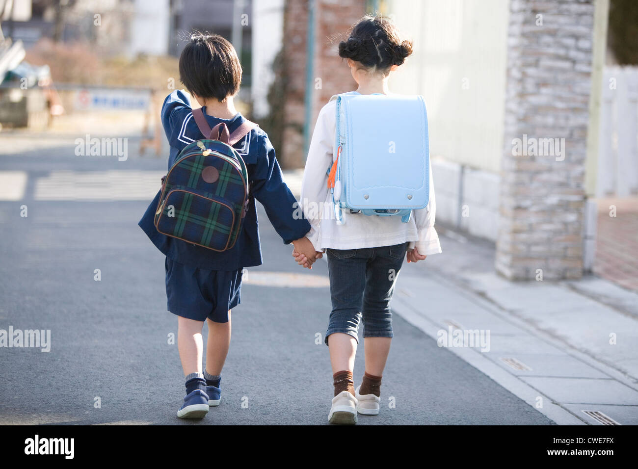 Two kids walking on road Stock Photo - Alamy