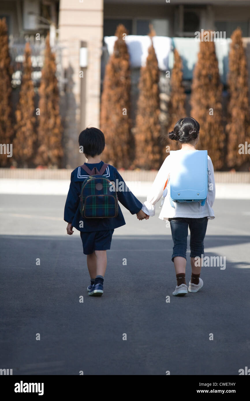 Two kids walking on road Stock Photo - Alamy