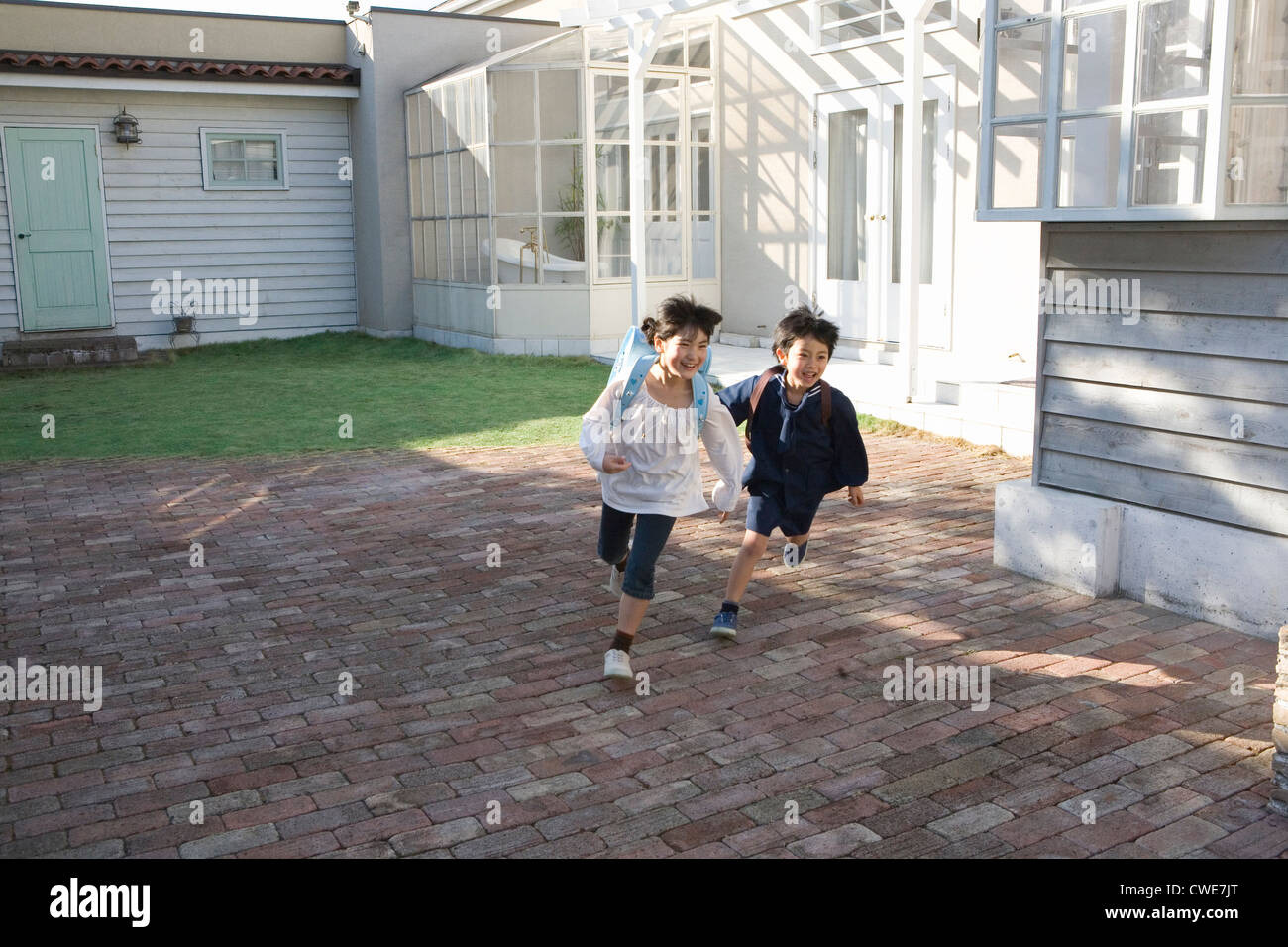 Two kids running on front yard Stock Photo - Alamy