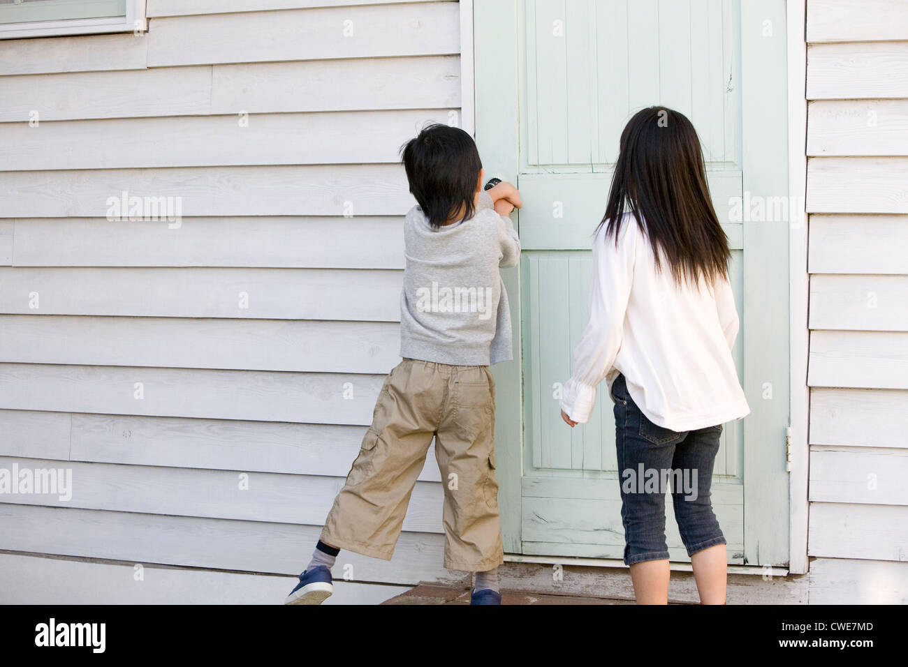 Two kids standing in front of door Stock Photo - Alamy