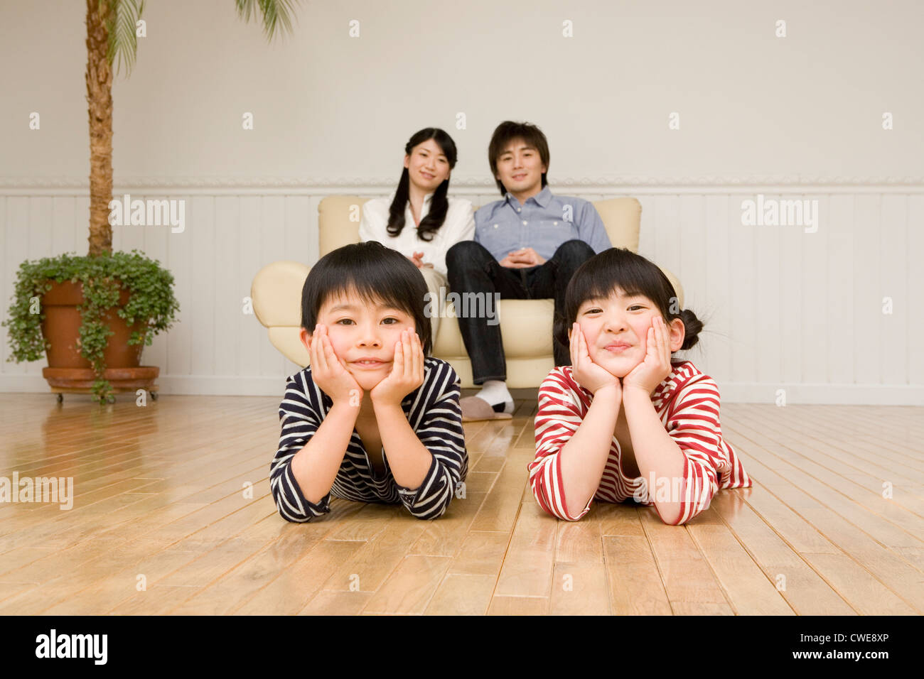 Parents sitting on sofa and children lying on wooden floor Stock Photo ...