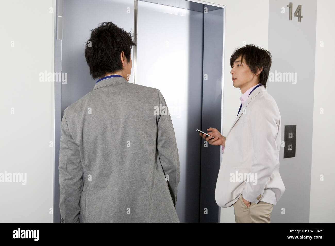 Two businessmen talking at elevator hall Stock Photo - Alamy