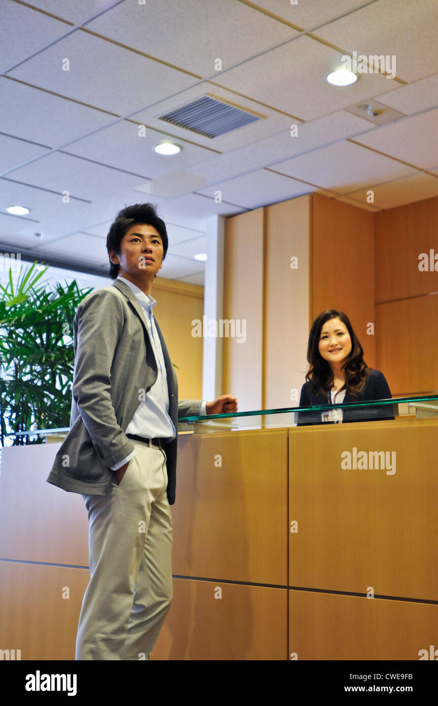 Visitor and receptionist looking away at front desk Stock Photo - Alamy