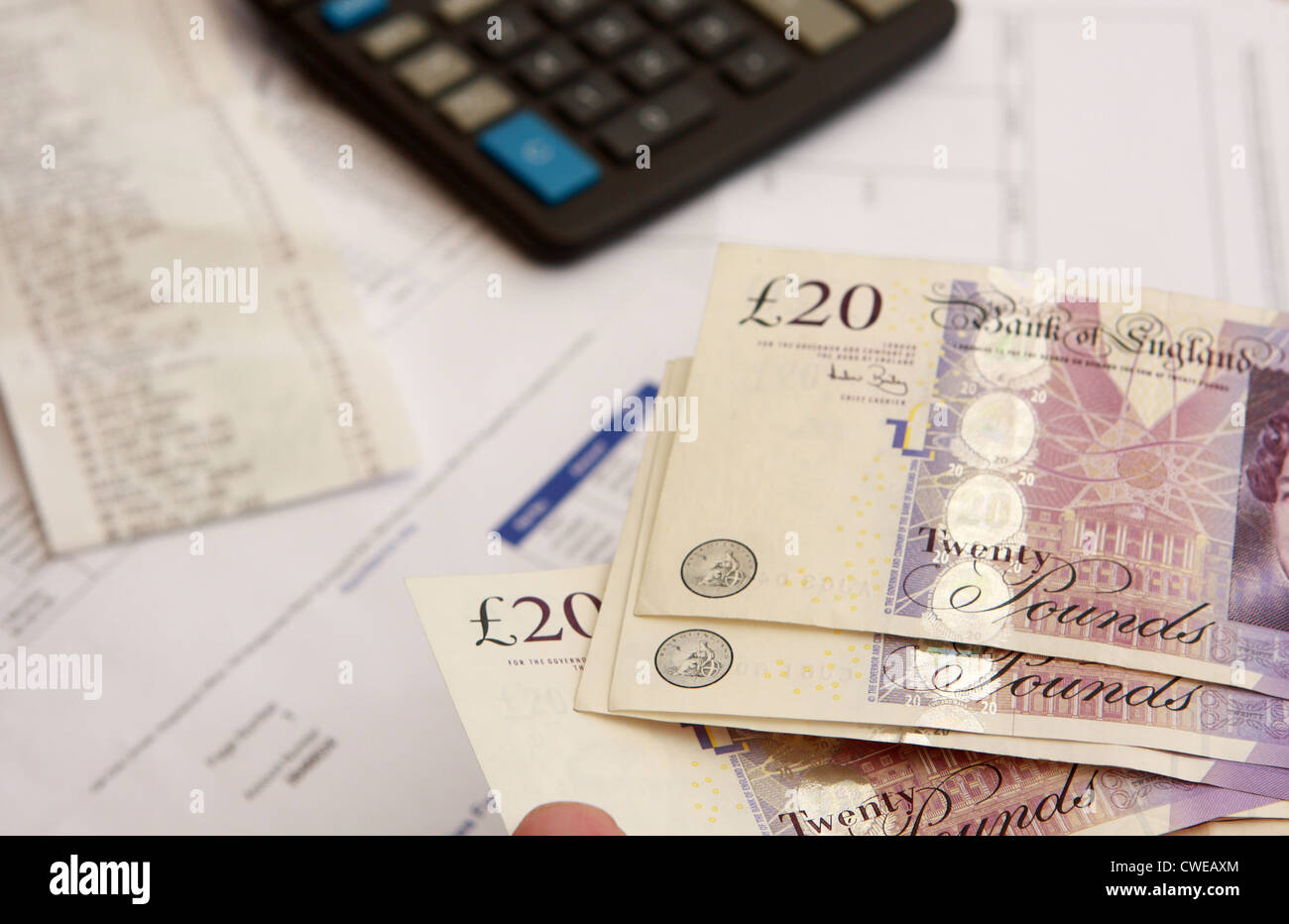 the tip of a thumb pulling a £20 note from a bundle of notes with a ...