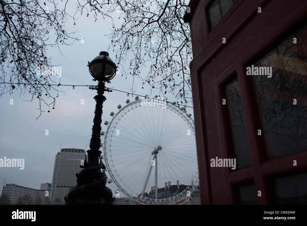 The London Eye silhouetted against a dull grey sky with a fancy street ...