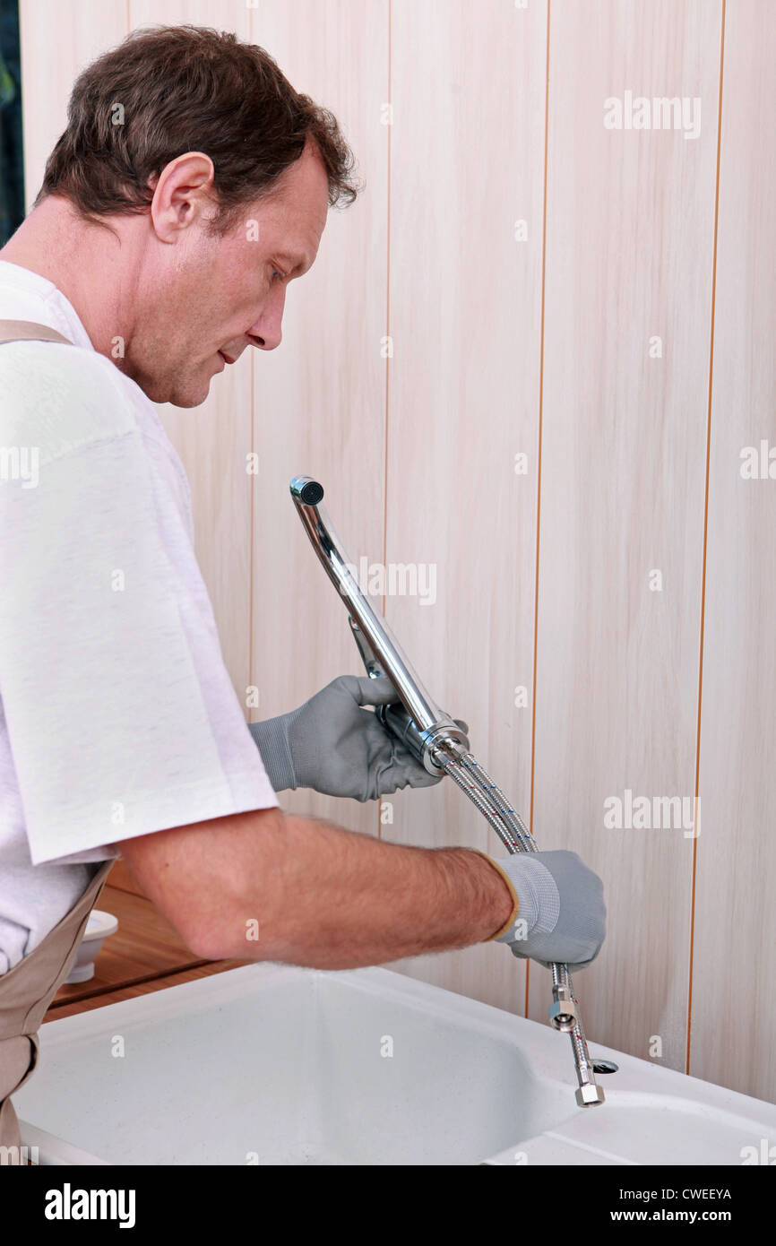 Pluber fitting a new tap Stock Photo - Alamy