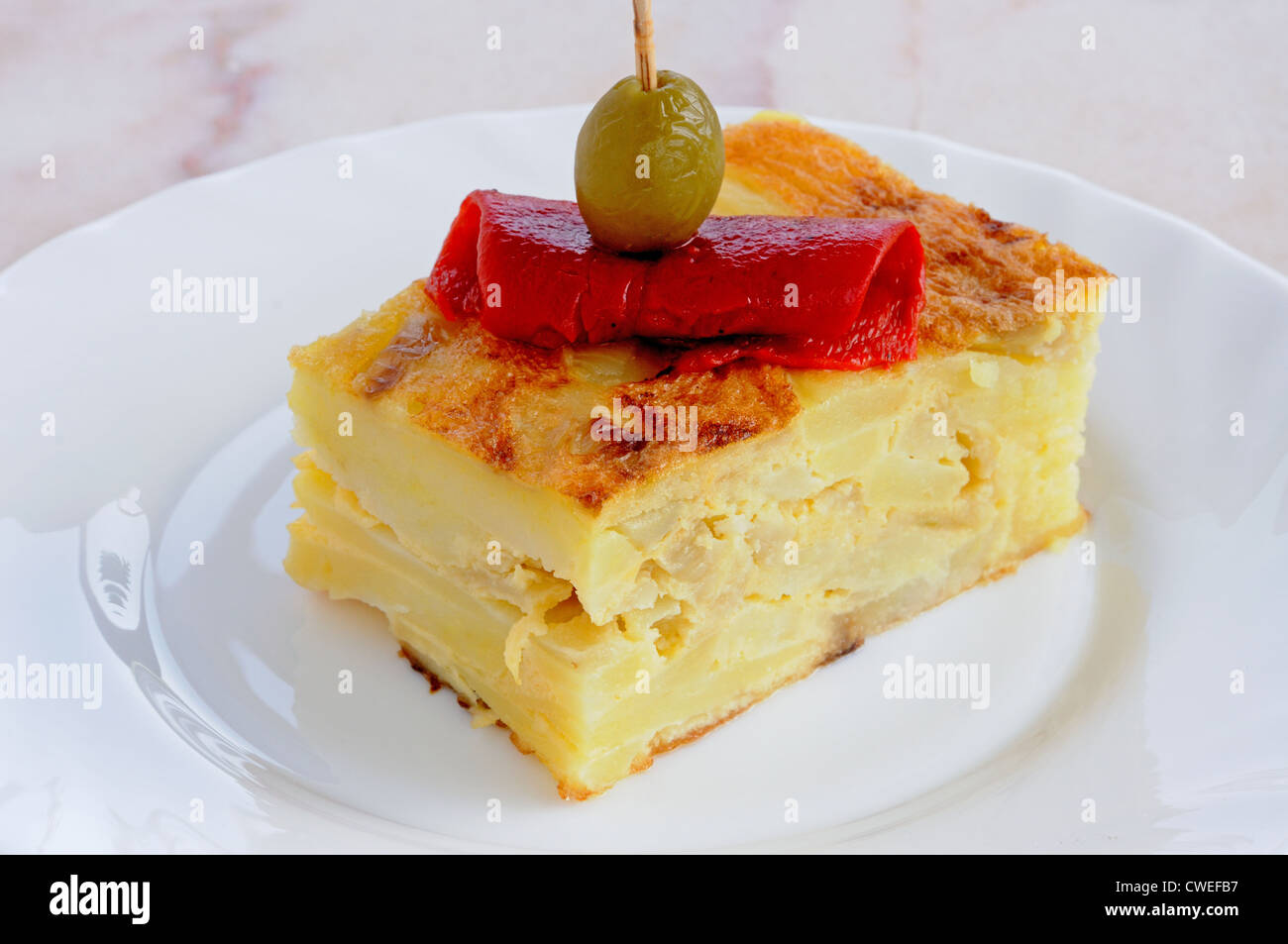 Tapas of Spanish tortilla topped with red pepper and a green olive ...