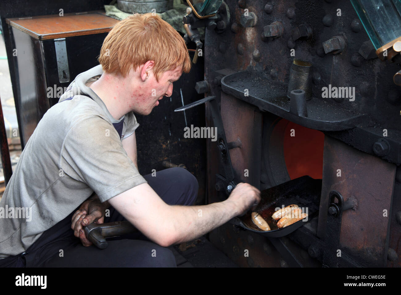 Steam engine engineer cooking sausages in the steam engine firebox ...