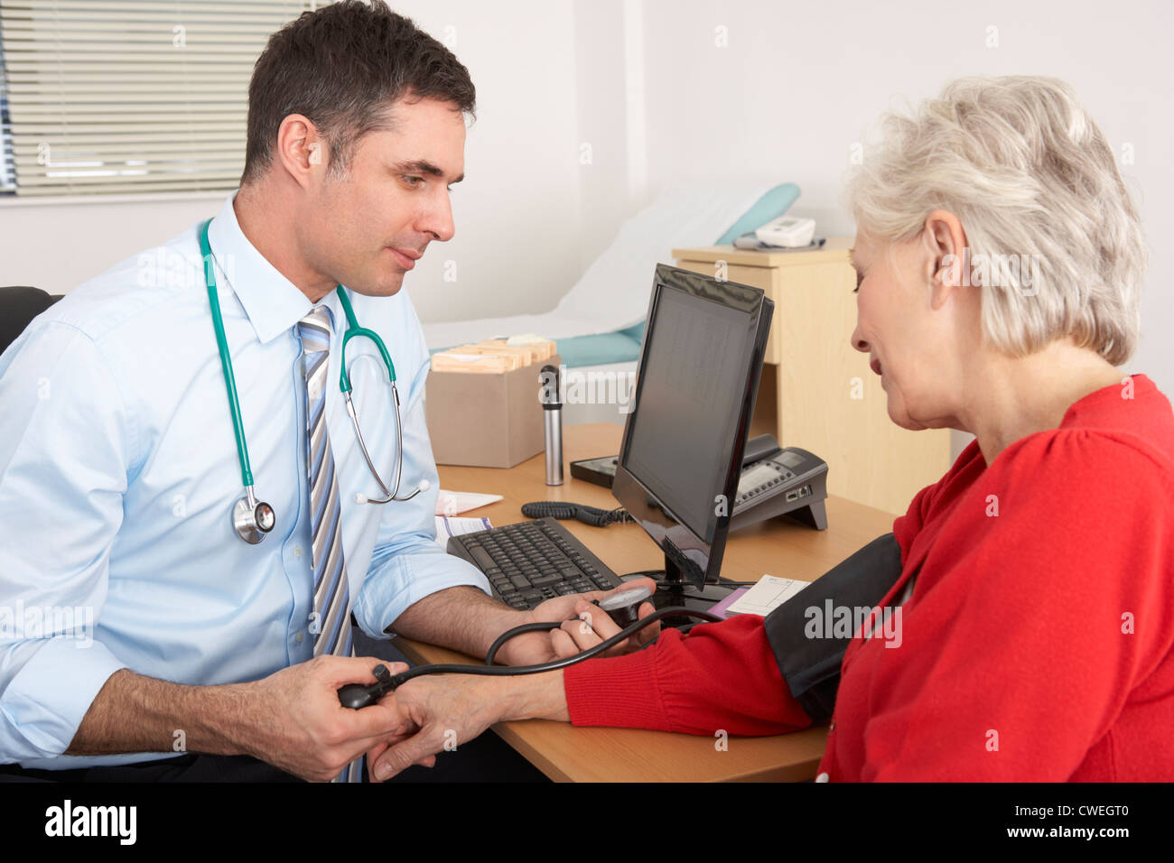 British doctor taking senior woman's blood pressure Stock Photo - Alamy