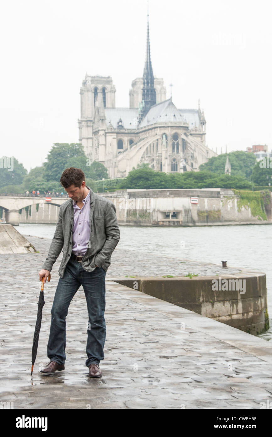 Sad man with an umbrella, standing in front of the Notre Dame Cathedral ...