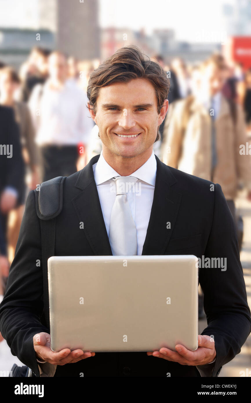 Male commuter in crowd using laptop Stock Photo - Alamy