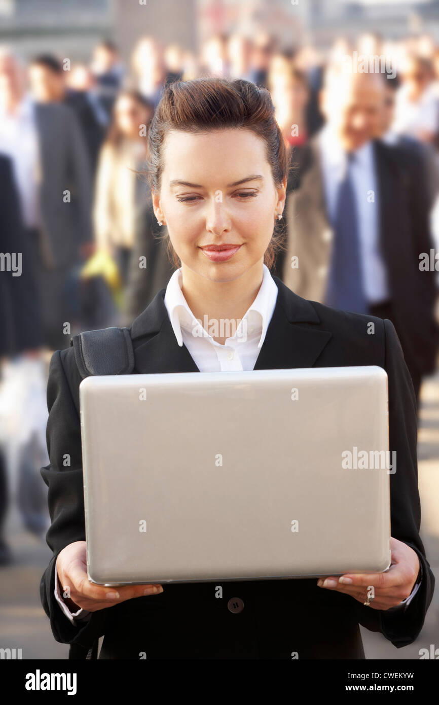 Female commuter in crowd using laptop Stock Photo - Alamy