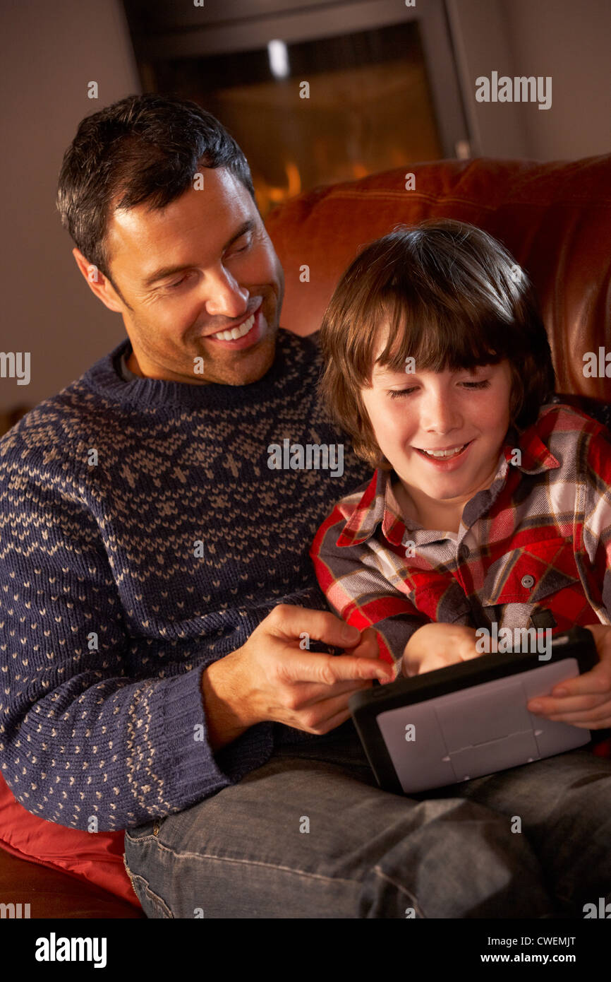 Father And Son Using Tablet Computer By Cosy Log Fire Stock Photo - Alamy
