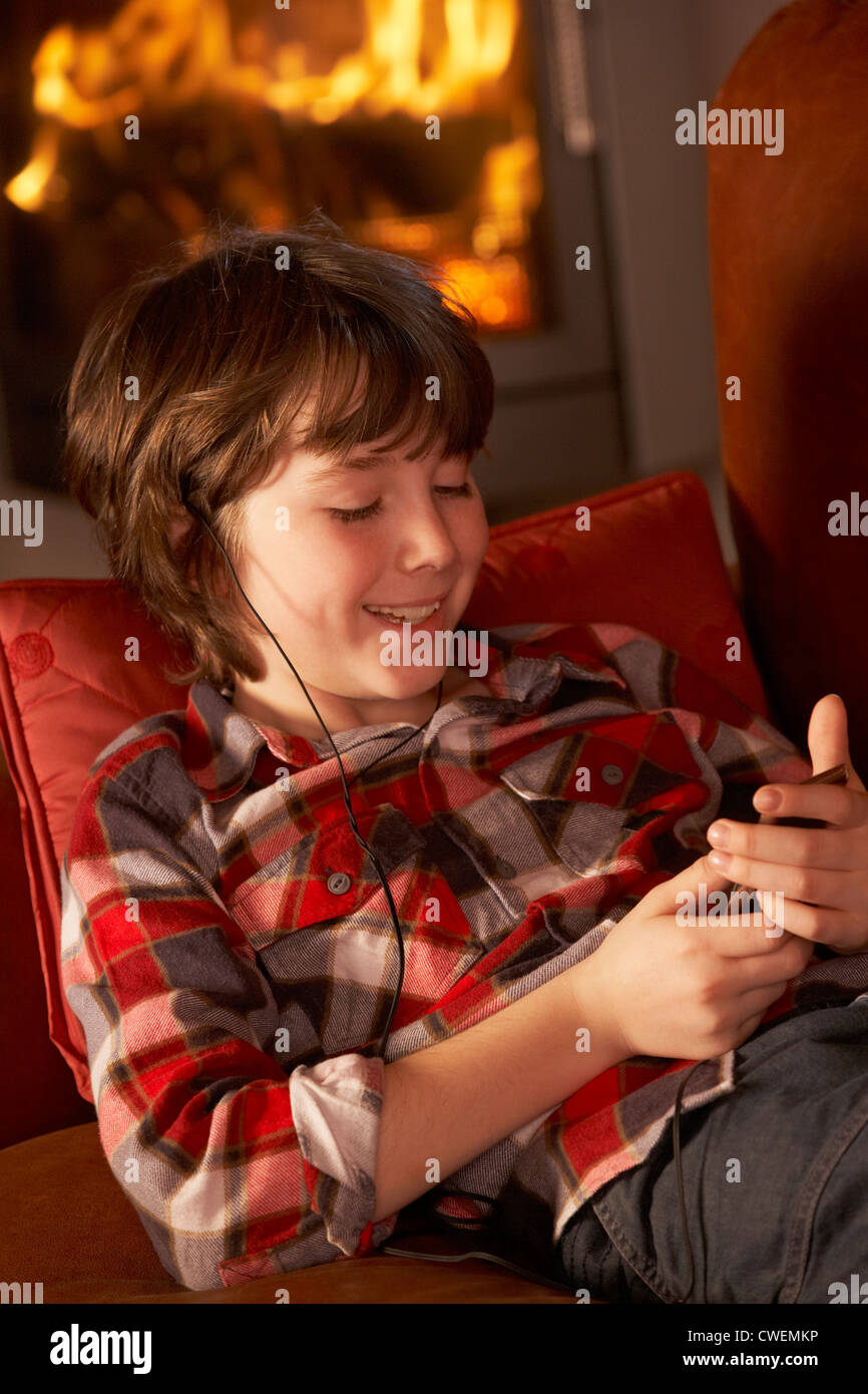 Young Boy Relaxing With MP3 Player By Cosy Log Fire Stock Photo - Alamy