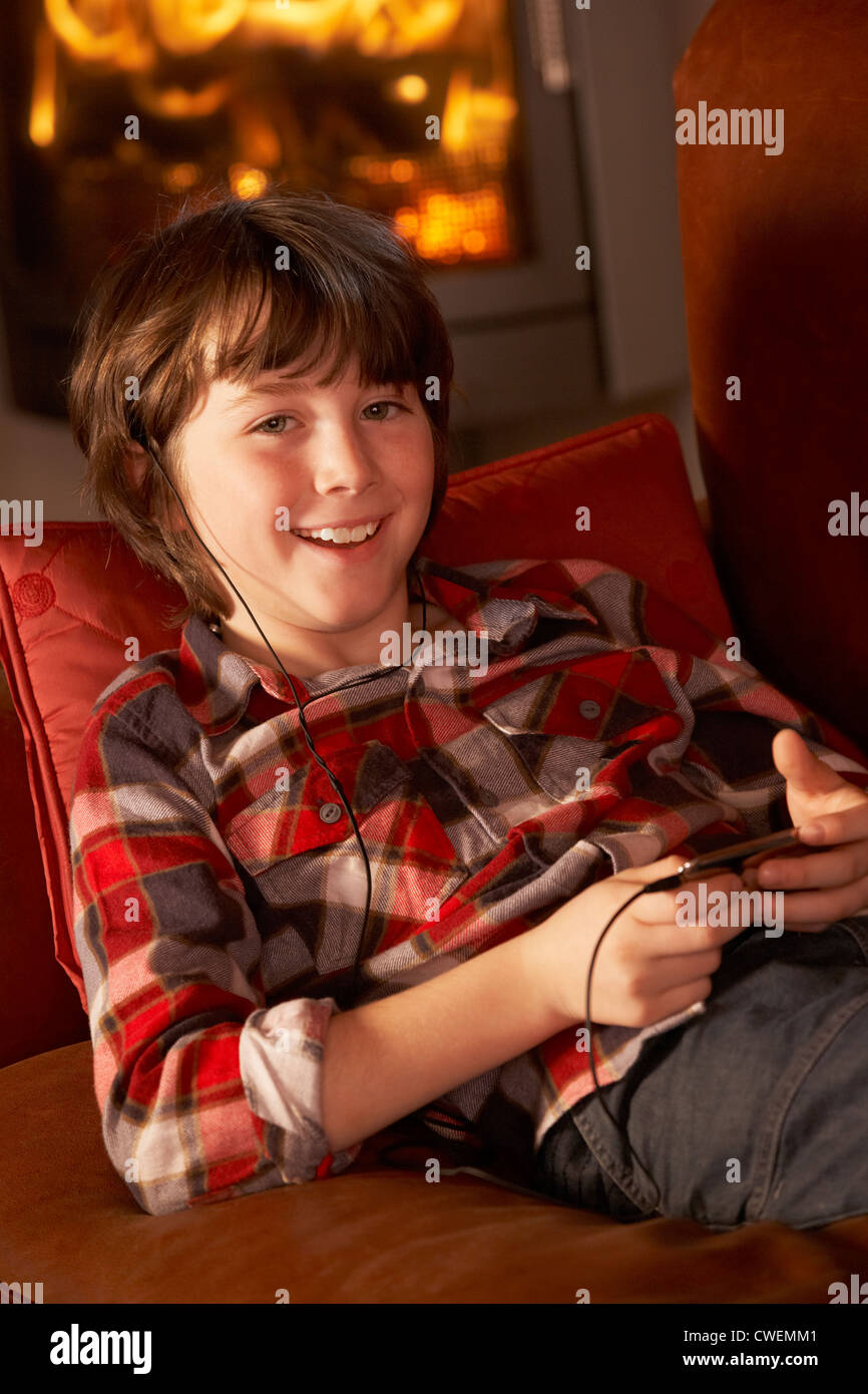 Young Boy Relaxing With MP3 Player By Cosy Log Fire Stock Photo - Alamy