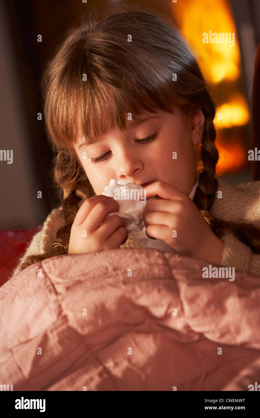 Sick Girl With Cold Resting On Sofa By Cosy Log Fire Stock Photo - Alamy