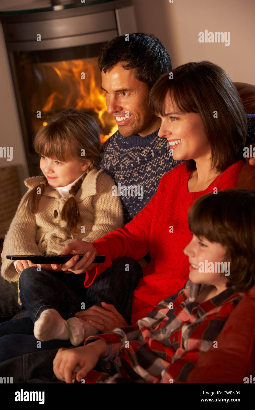 Family Relaxing Watching TV By Cosy Log Fire Stock Photo - Alamy