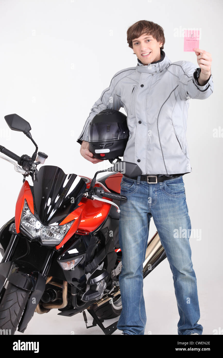 Young man holding driving license stood next to motorcycle Stock Photo ...