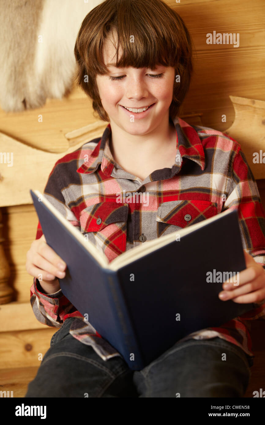 Young Boy Sitting On Wooden Seat Reading Book Stock Photo - Alamy