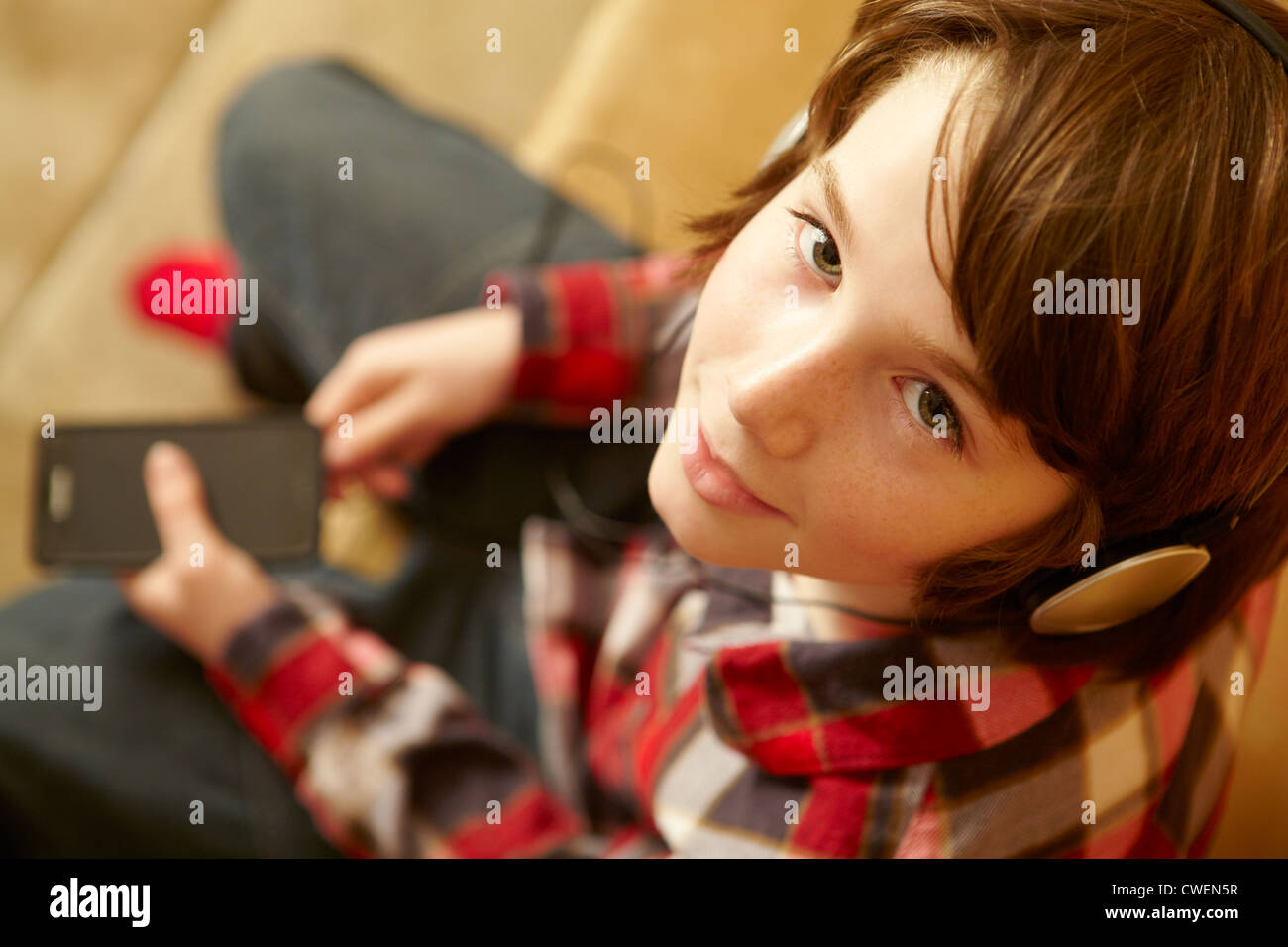 Young Boy Sitting On Wooden Seat Listening To MP3 Player Stock Photo ...