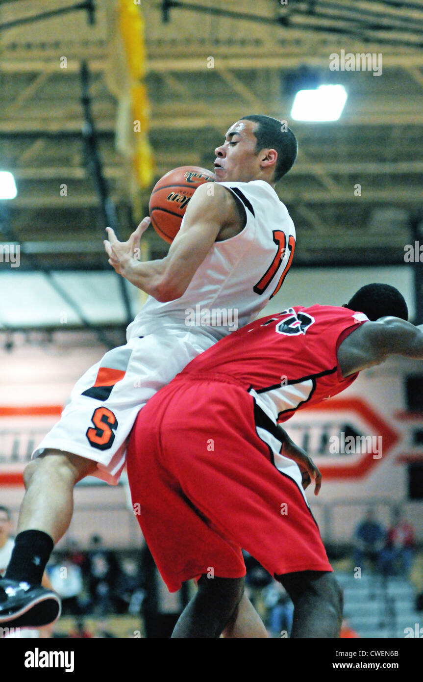 Basketball player is upended by a floor-bound opponent during a high ...