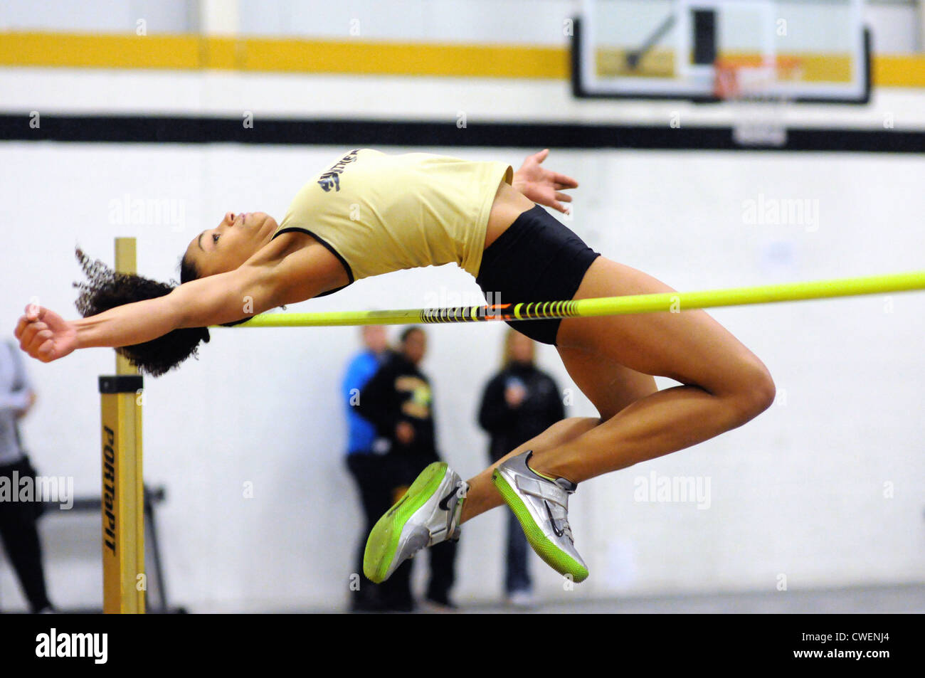 High Jump Female athlete clears the bar on a high jump pass during a high school indoor track ...