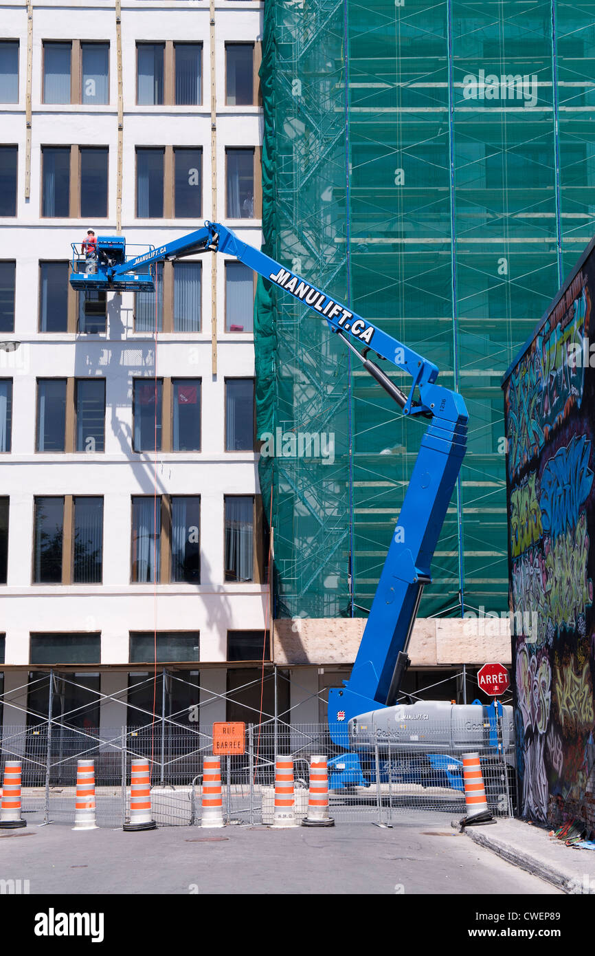 Construction worker on a power lift working on the facade of a building ...