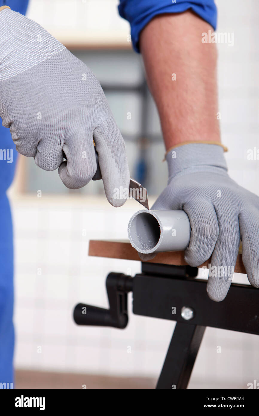 Plumber cutting plastic pipe to size Stock Photo - Alamy