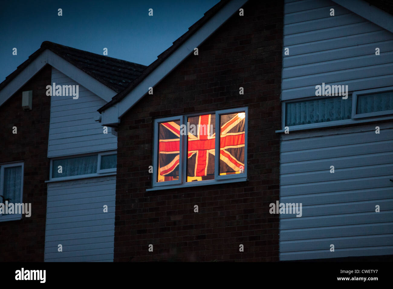 A Union Jack flag displayed in a bedroom window illuminated by an ...